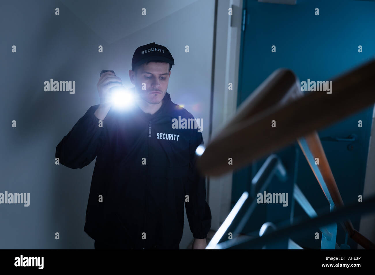 Male Security Guard Standing On Staircase Holding Flashlight Stock ...