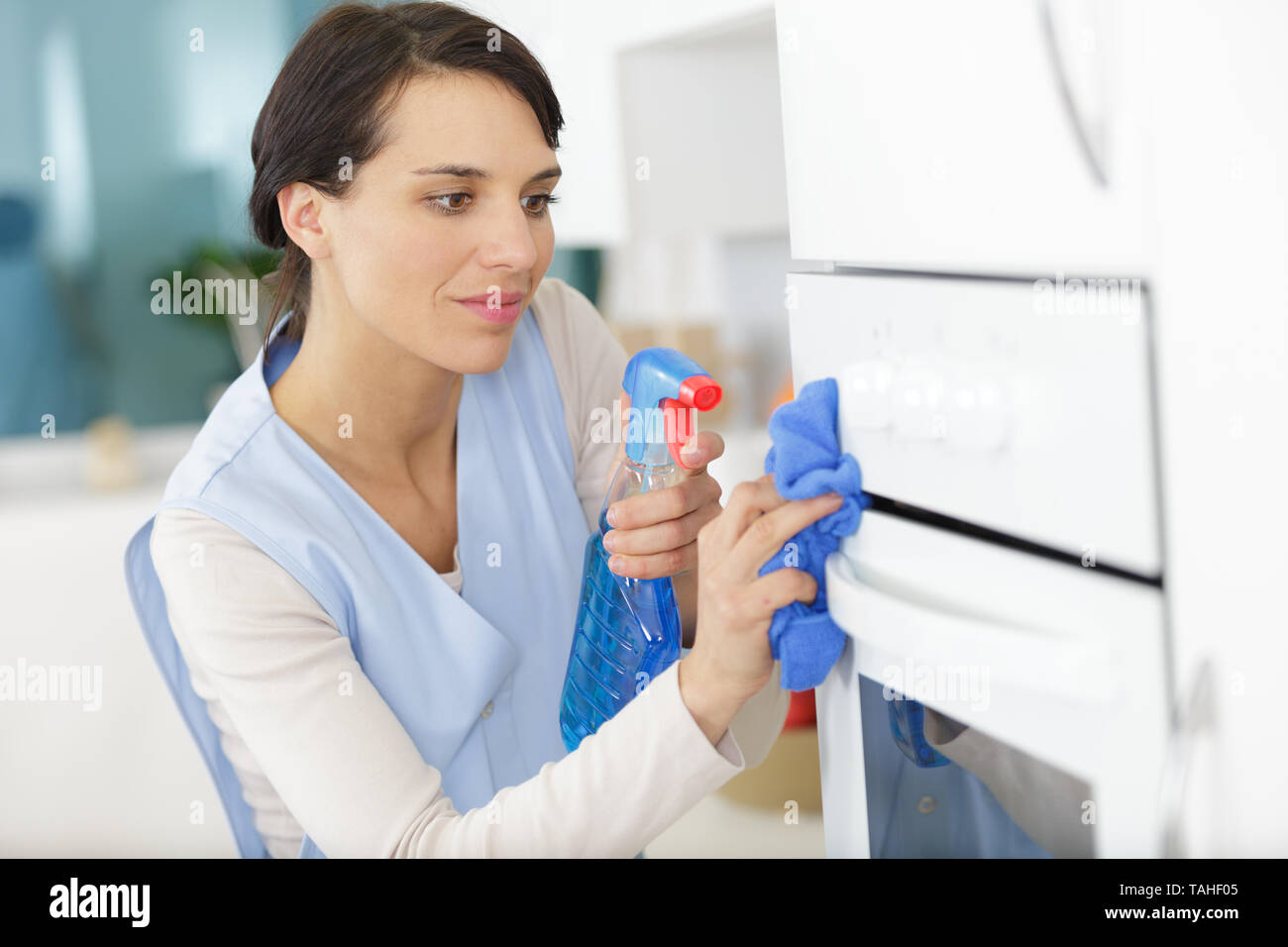beautiful woman cleaning oven with spray bottle and rag Stock Photo - Alamy