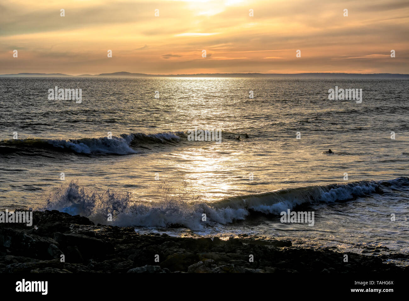 Three Surfers enjoy the sunset as thet wait for awave, Rest Bay ...
