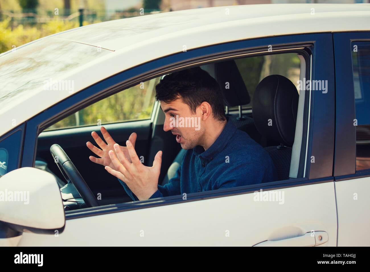 Angry man driving a vehicle arguing and gesturing shaking his hands ...