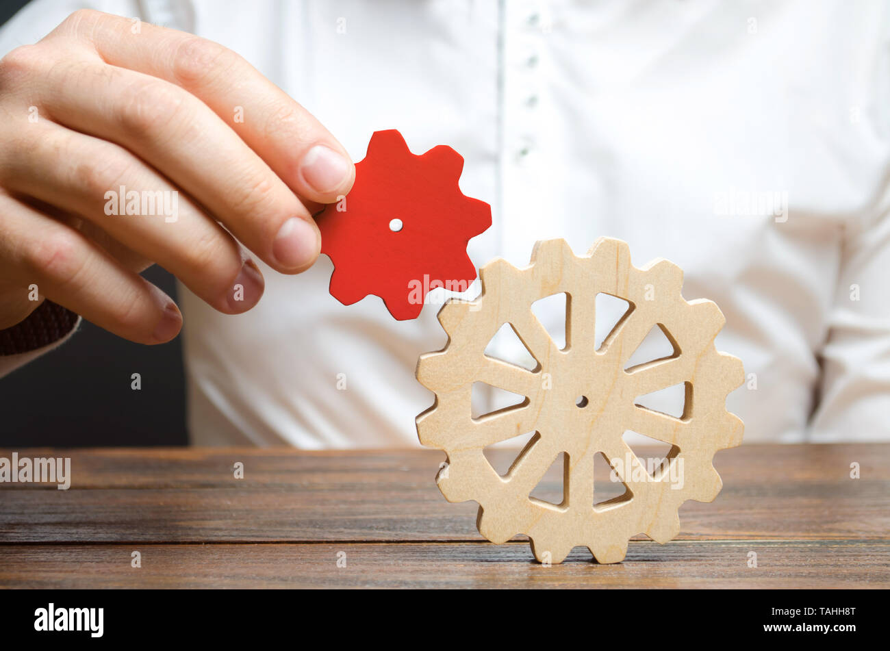 Businessman connects a small red gear to a large gear wheel. Symbolism ...