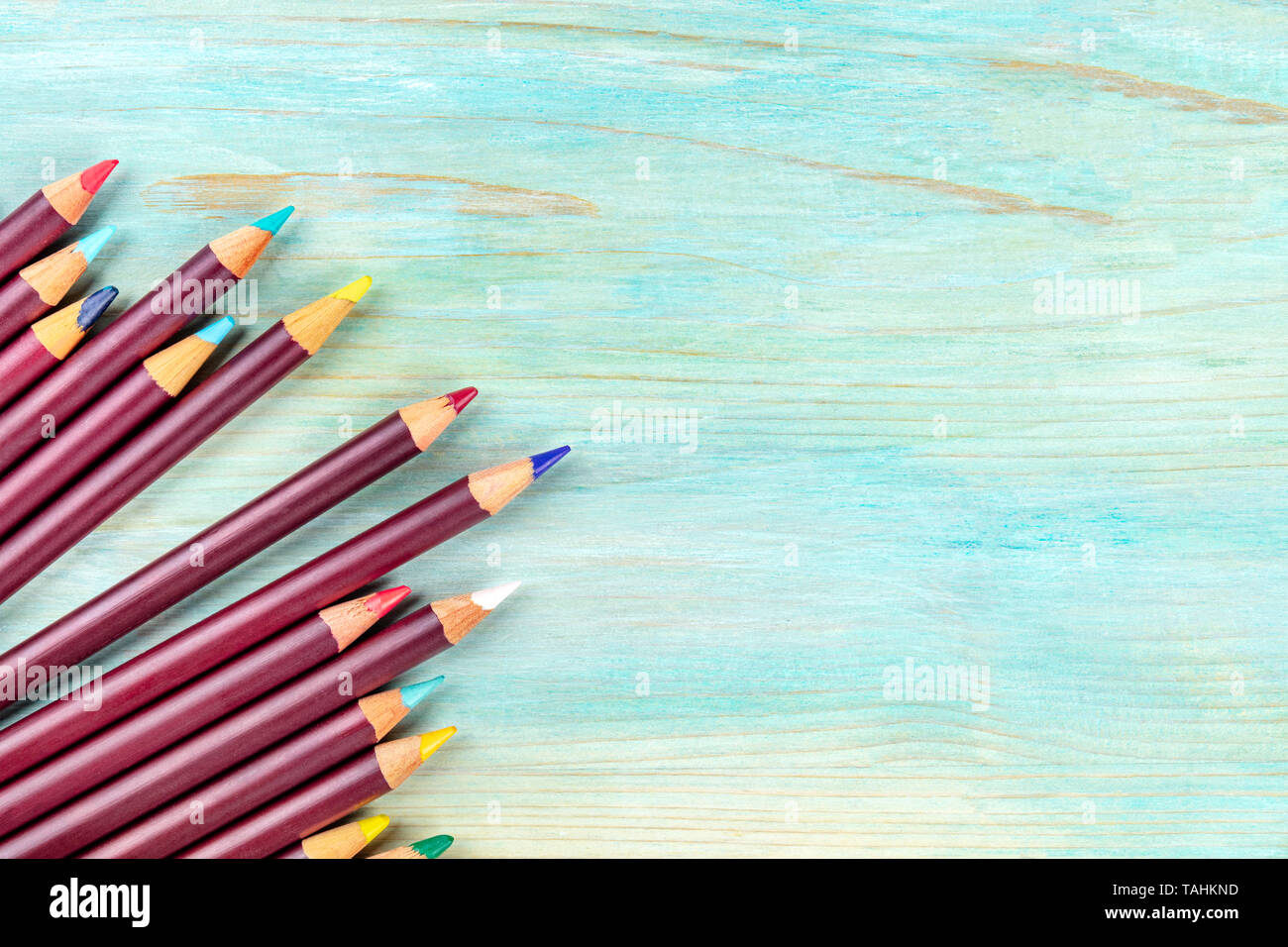 Colored pencils, shot from the top on a vibrant teal blue background ...