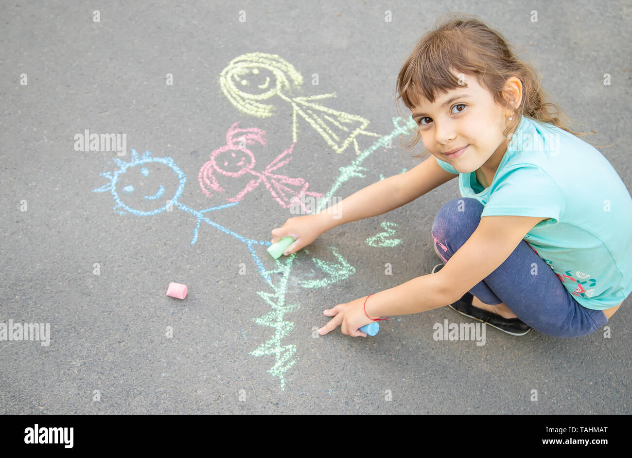 Child draws a family on the pavement with chalk. Selective focus ...