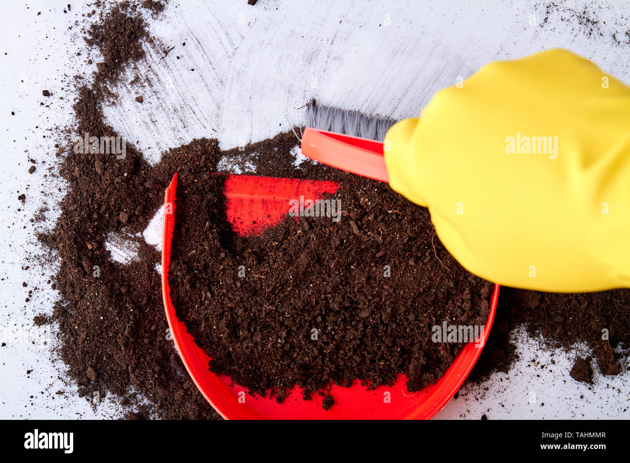 Close up of sweeping soil with red brush and dustpan. Person with ...