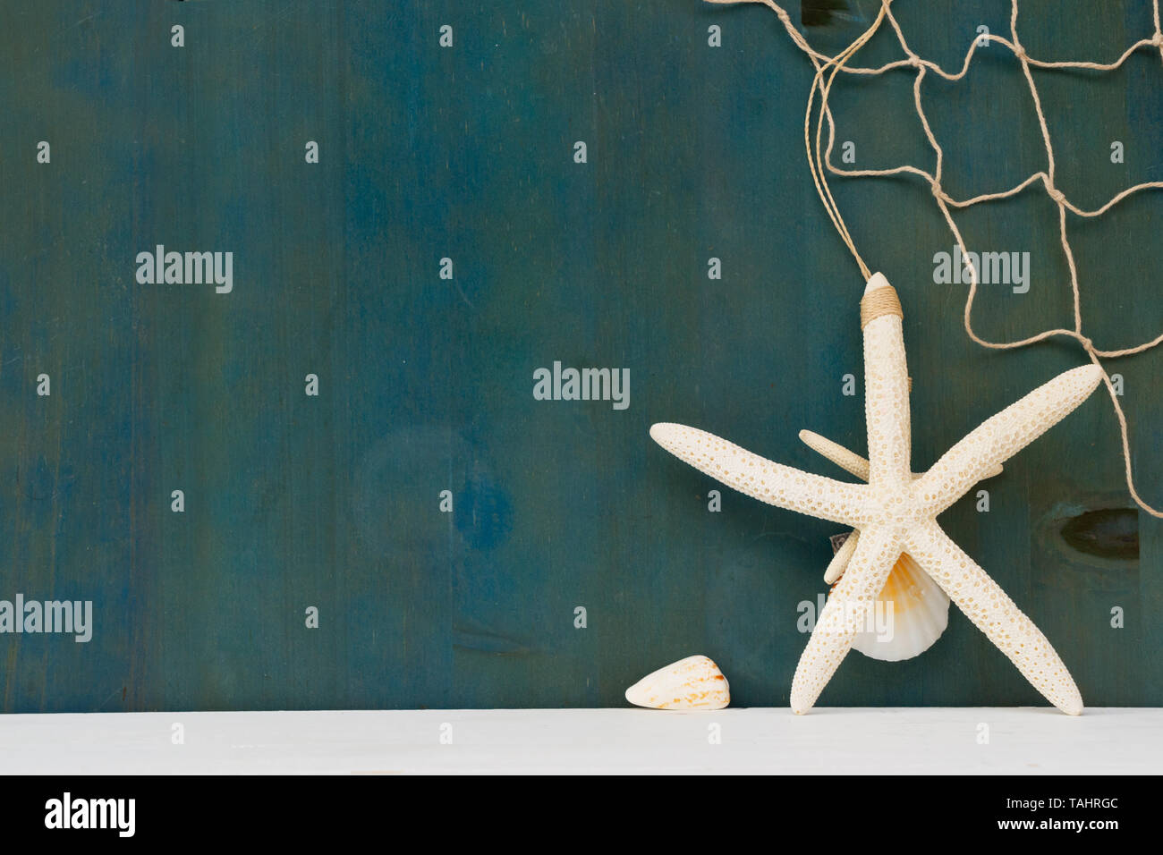Summer sea still life with starfish and fishing net, copy space on blue ...