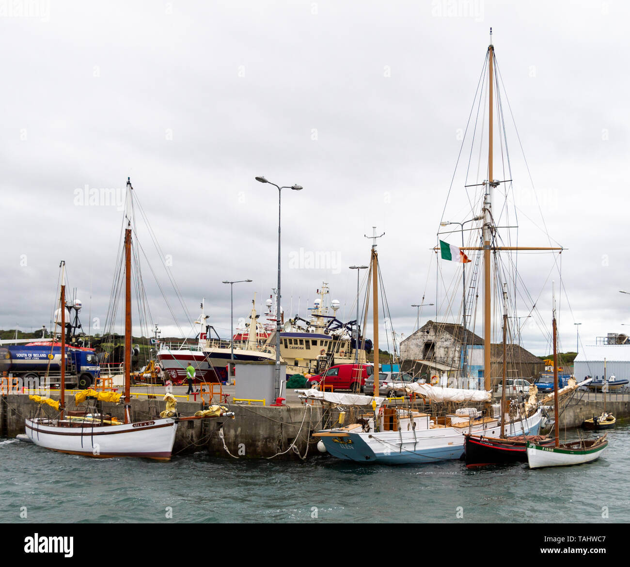 Traditional wooden sailing ships alongside a pier with modern trawlers ...