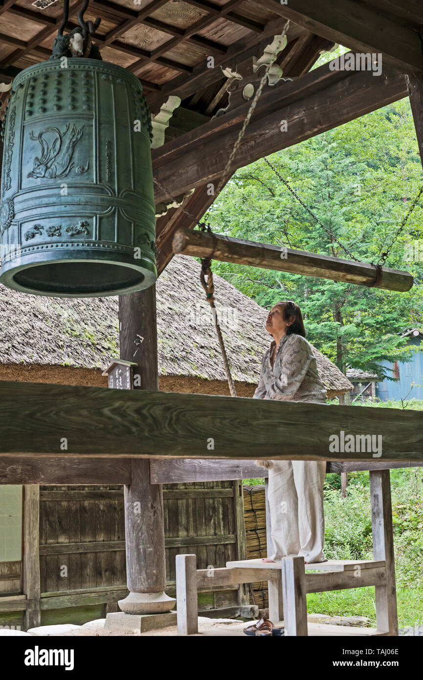 Asian Lady pulling on rope to ring the bell in the belfry at the ...