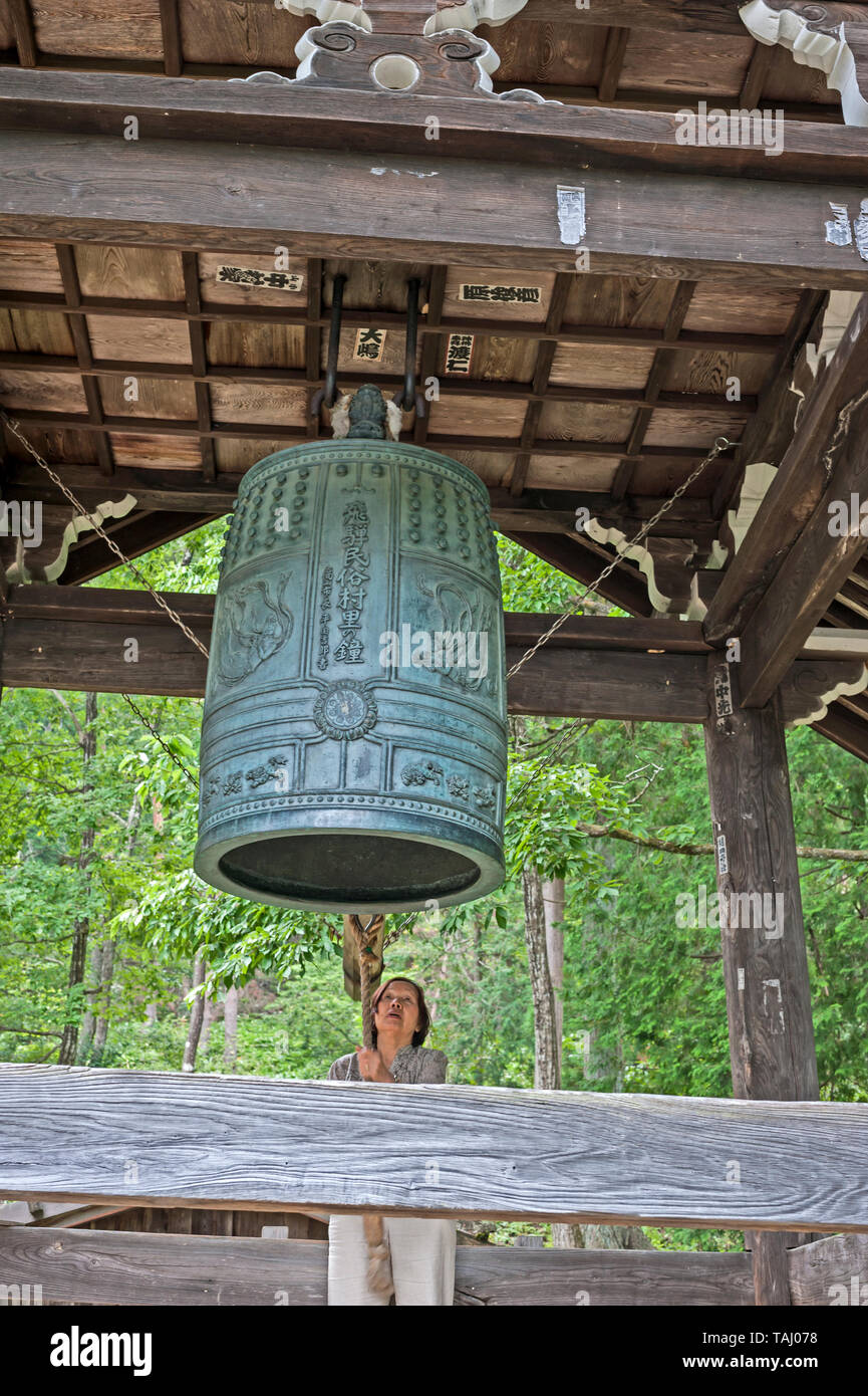 Asian Lady pulling on rope to ring the bell in the belfry at the ...