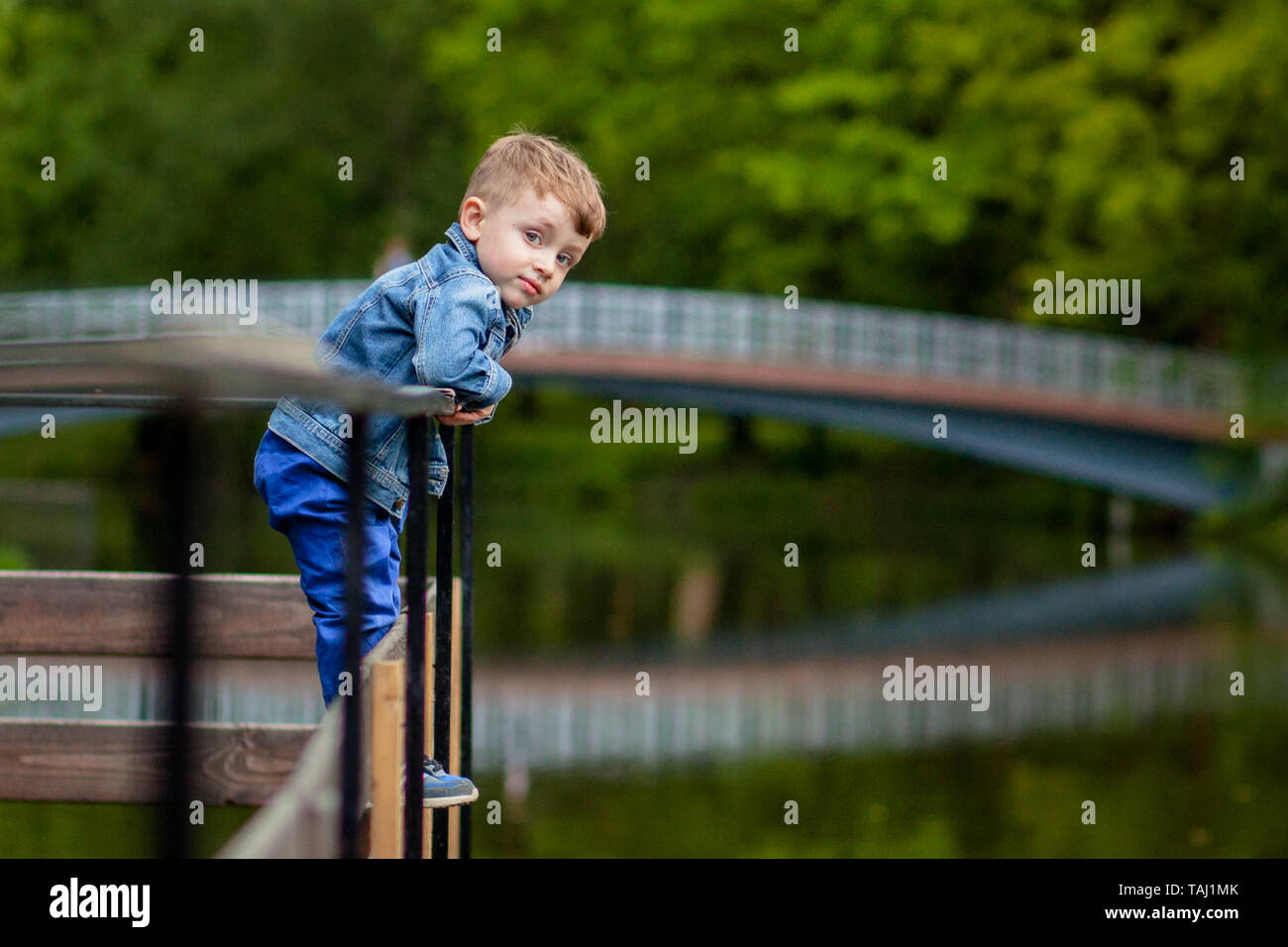 A little boy climbs a bridge railing in the park. The threat of ...