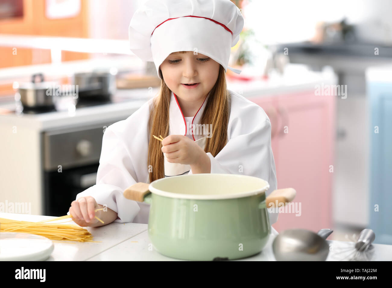 Cute little girl dressed as chef playing at home Stock Photo - Alamy