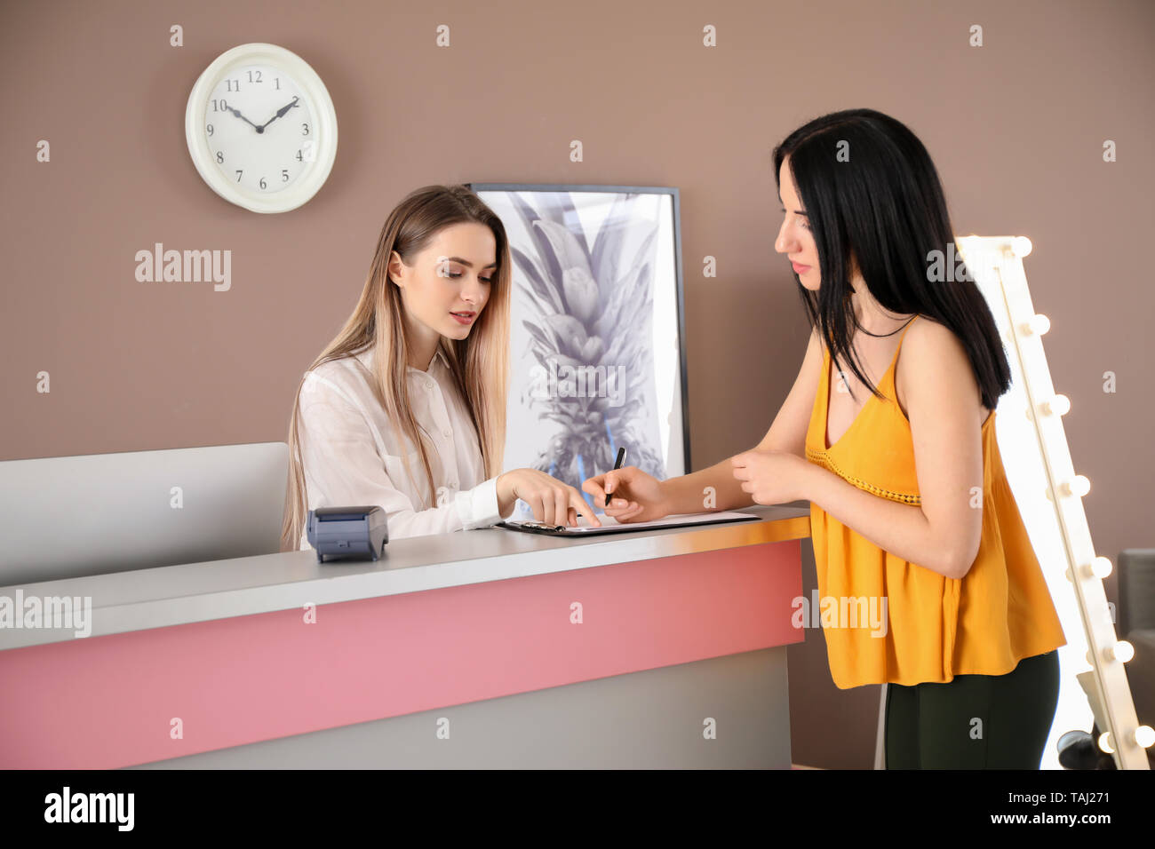 Young woman booking room in hotel at reception Stock Photo - Alamy