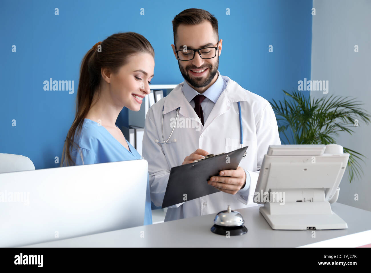 Doctor and female receptionist near desk in clinic Stock Photo - Alamy