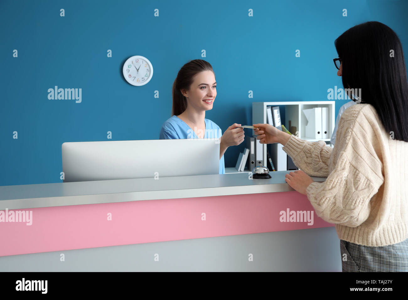 Female receptionist receiving payment for medical service from patient ...