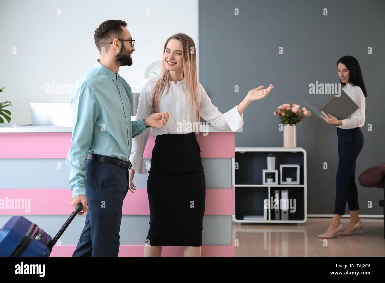 Young man and hostess at reception desk in hotel Stock Photo - Alamy