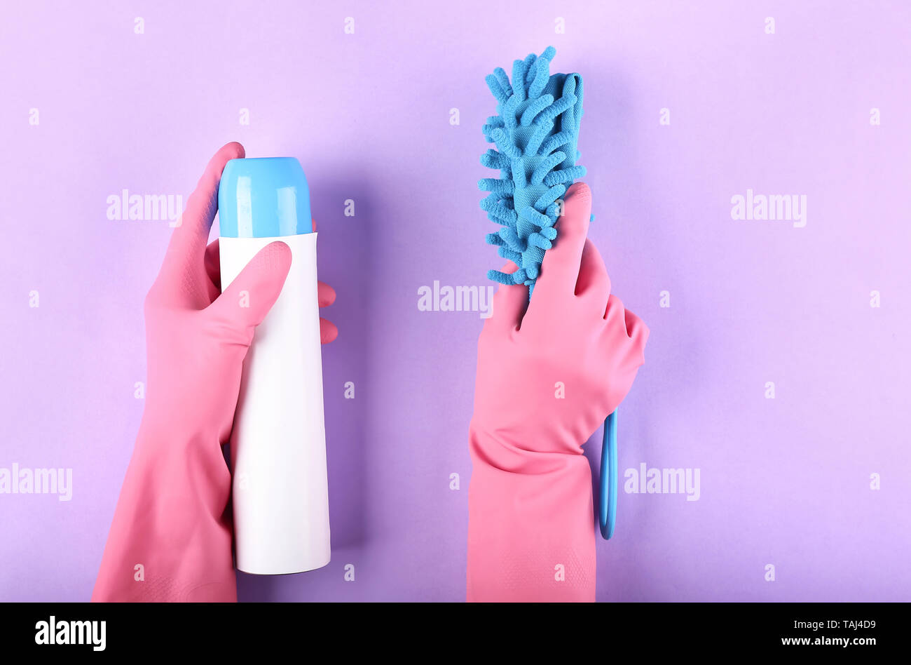 Hands of female janitor with brush and detergent on color background ...