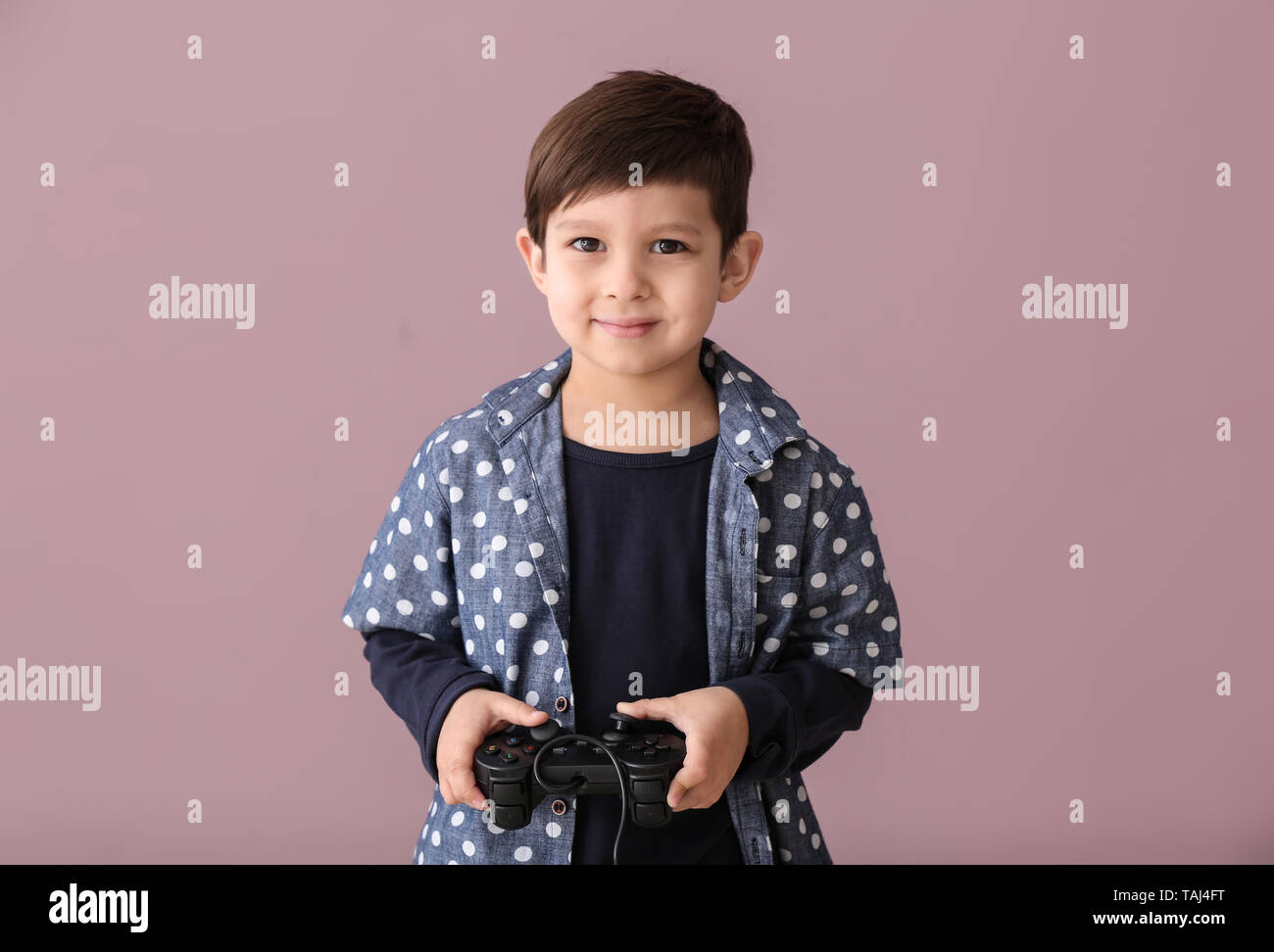 Cute boy playing video games on color background Stock Photo - Alamy