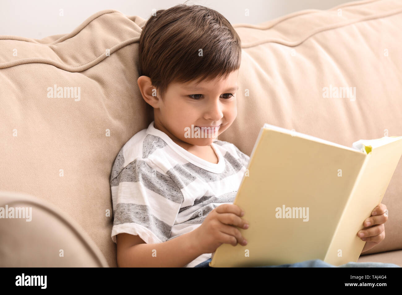 Cute little boy reading book at home Stock Photo - Alamy