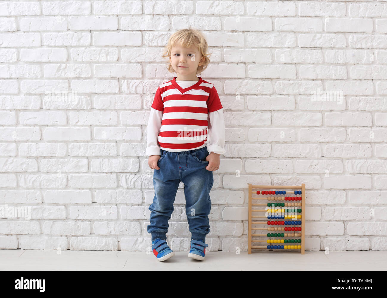 Portrait of cute little boy with abacus near white brick wall Stock ...
