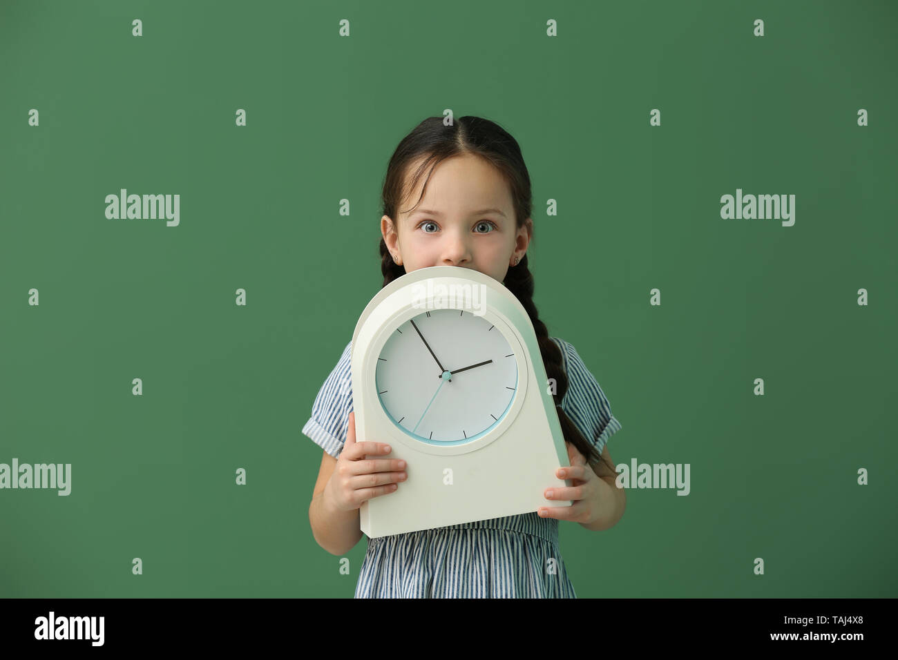 Portrait of cute little girl with clock on color background Stock Photo ...
