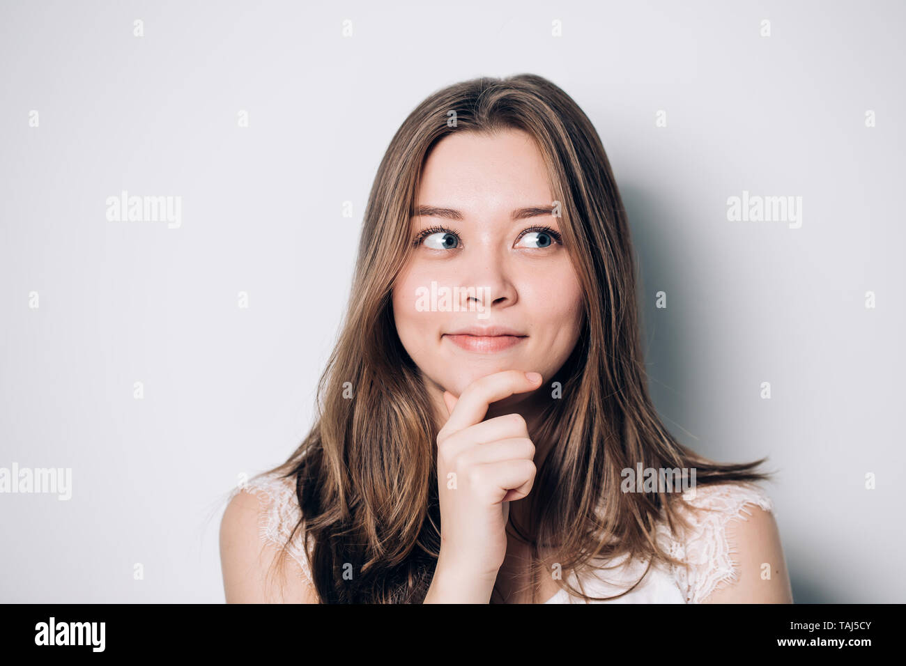 Beautiful woman looking aside holding hand under chin indenting to ...