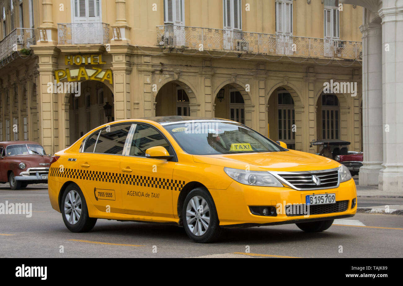 Havana, Cuba - A modern taxi cab passes in front of Hotel Plaza near ...