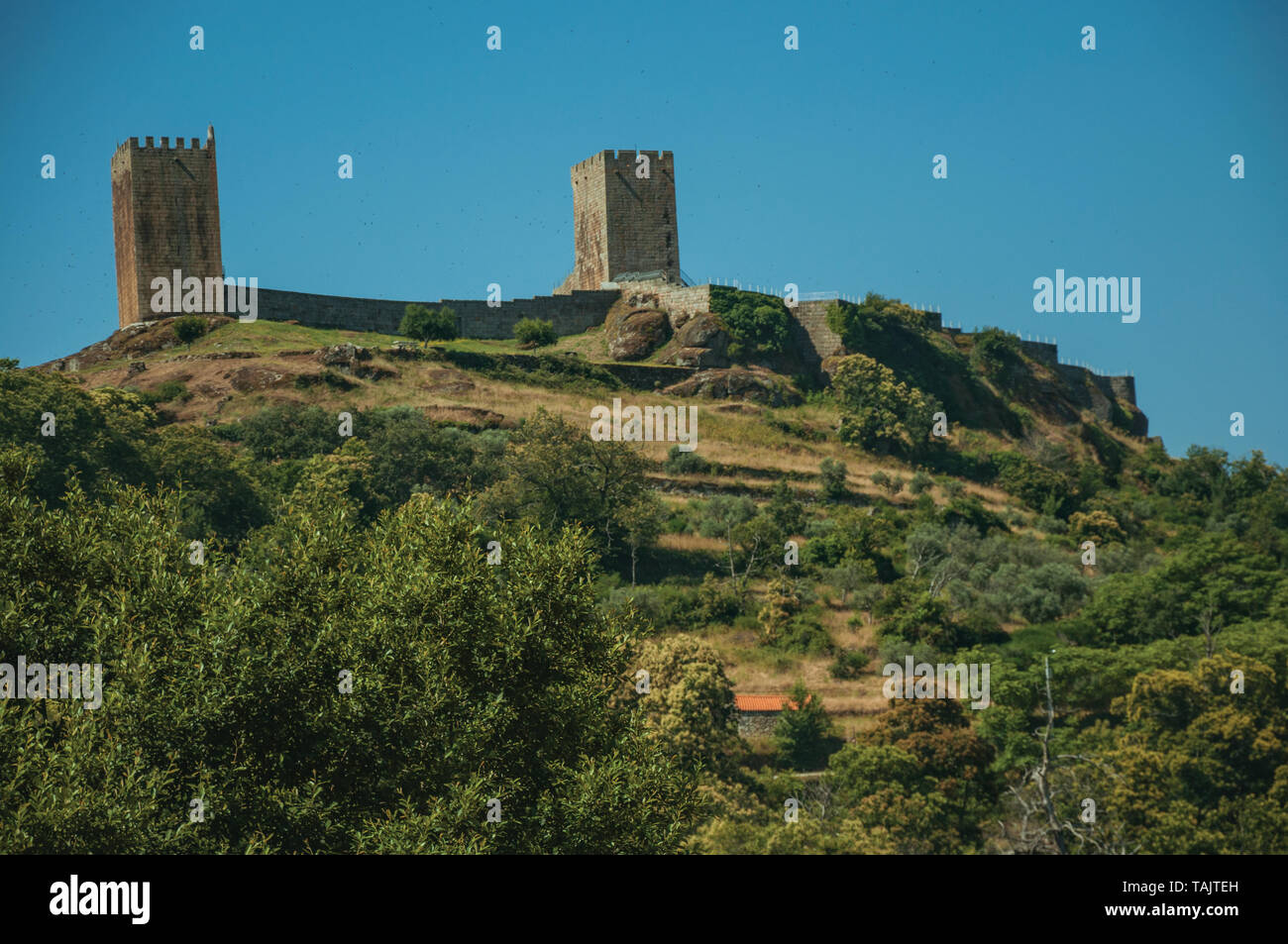 Hilly landscape with trees and rocks and the towers of Linhares da ...