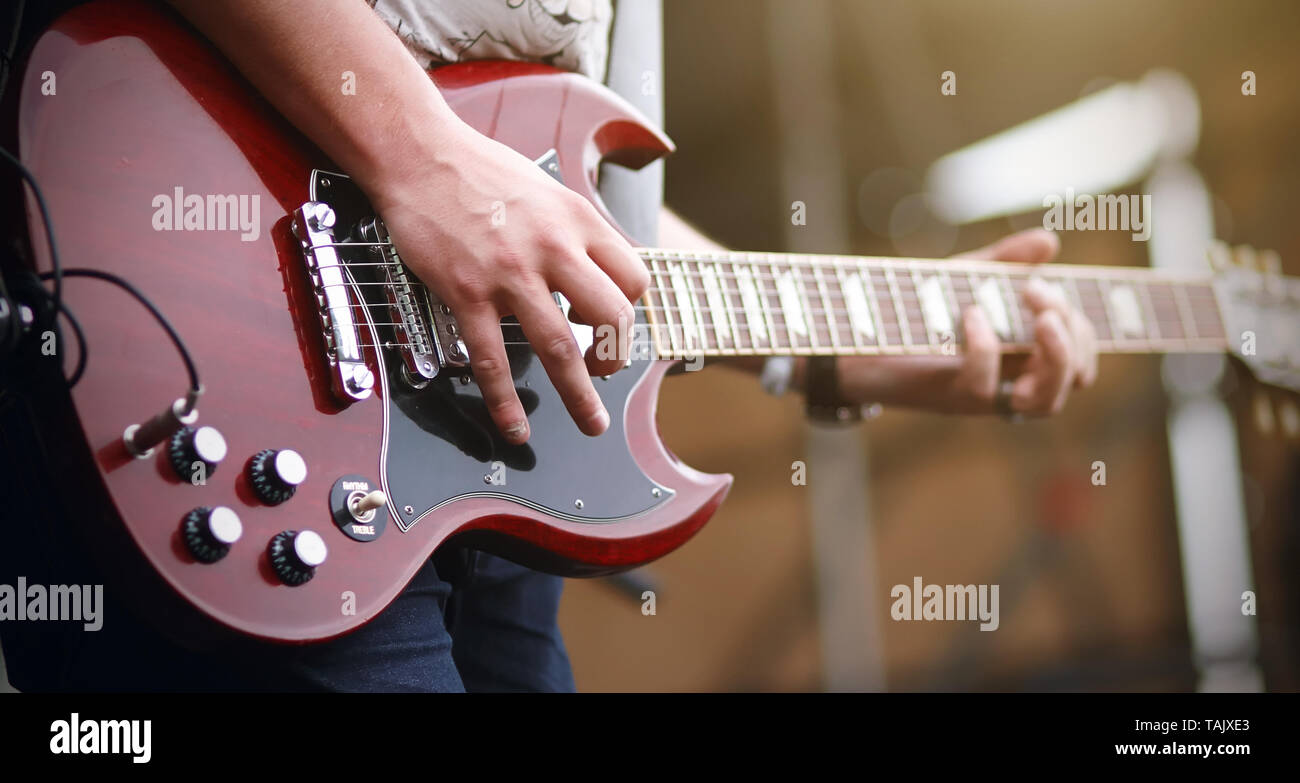 A man plays a melody on a red gothic six-string electric guitar on ...