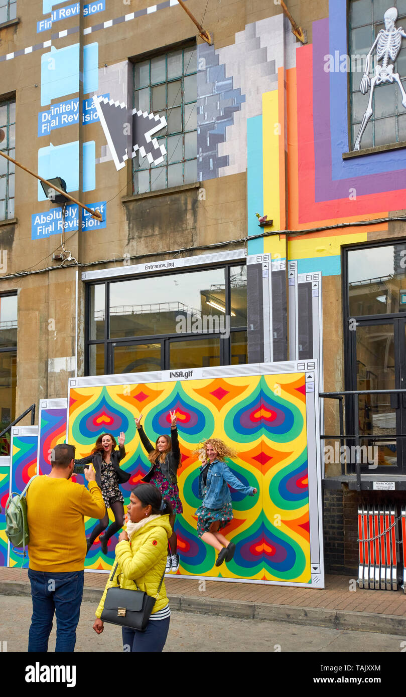 LONDON SPITALFIELDS BRICK LANE AREA PEOPLE JUMPING FOR JOY IN FRONT OF ...