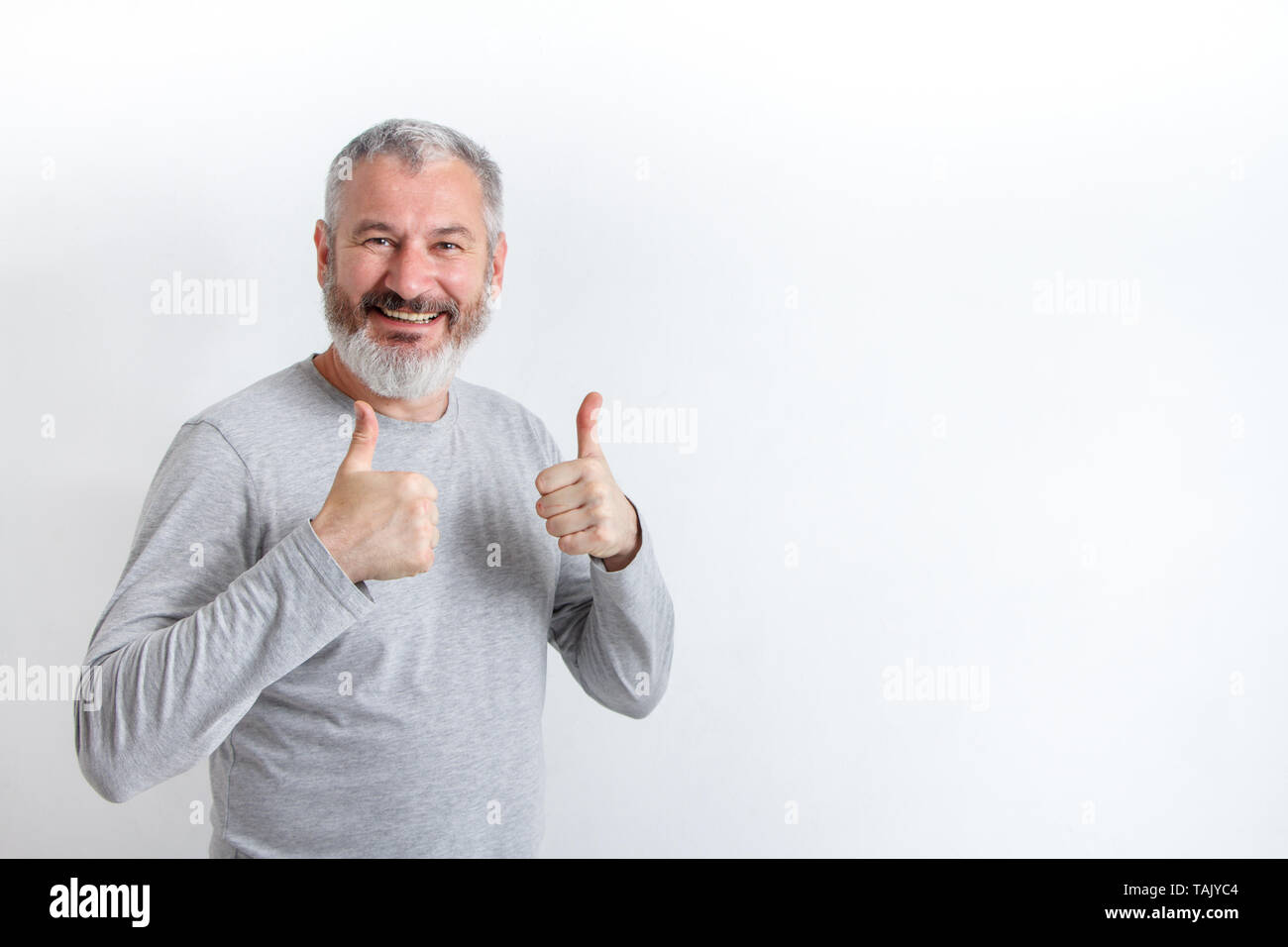 Adult happy gray-haired man with a beard showing thumbs up on a white ...