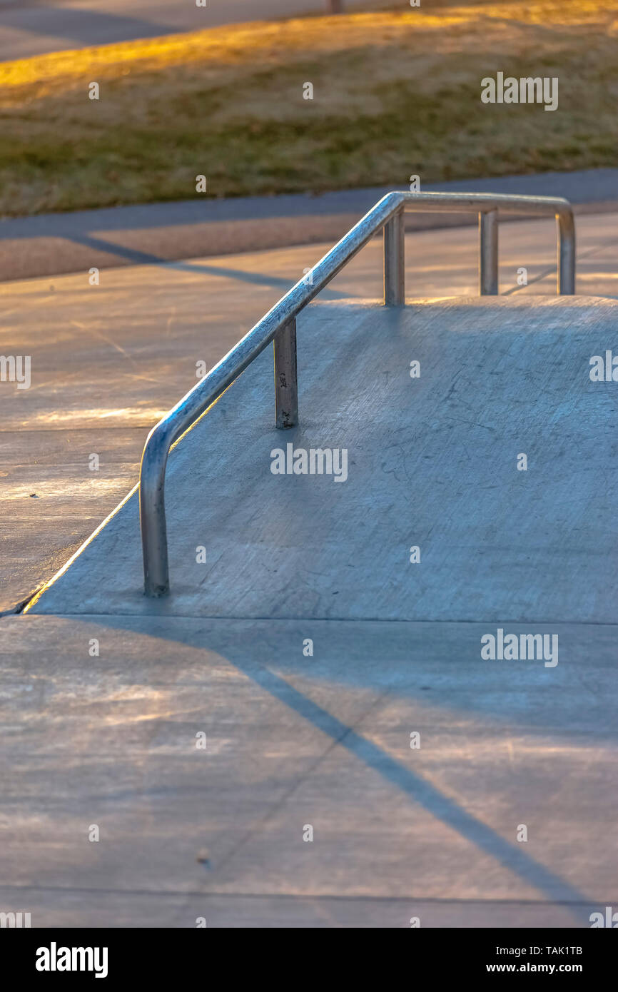 lose up of an inclined concrete ramp at a park lit by sunlight on a ...