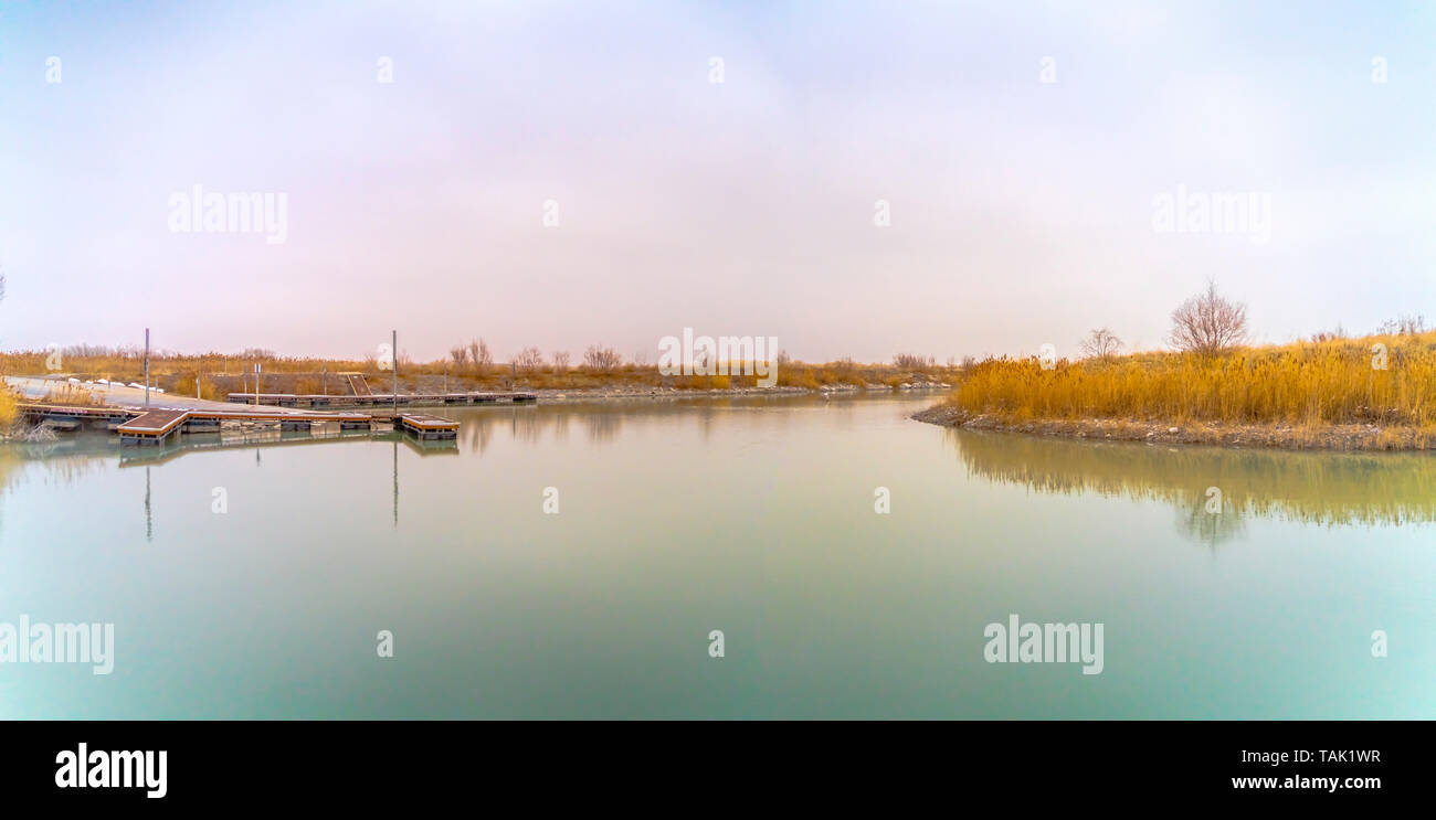 Gleaming lake with reflections of lush grasses and cloudy sky on its ...