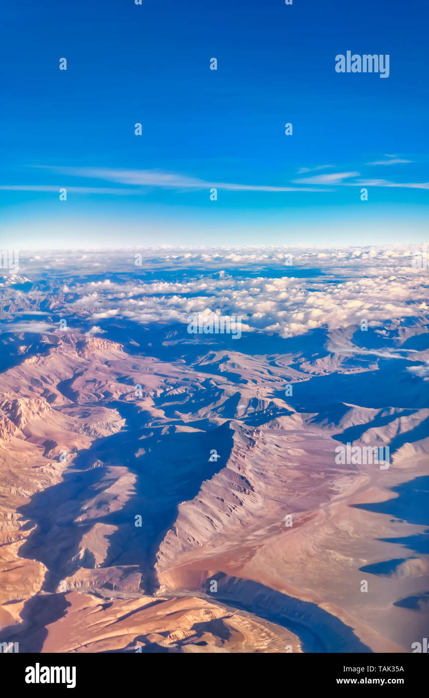 A thin layer of monsoon clouds over the barren mountains of the Zanskar ...