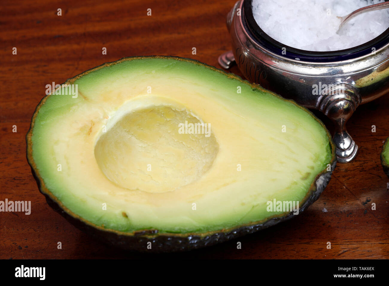 Avocado cut in half on a plain wooden table Stock Photo - Alamy