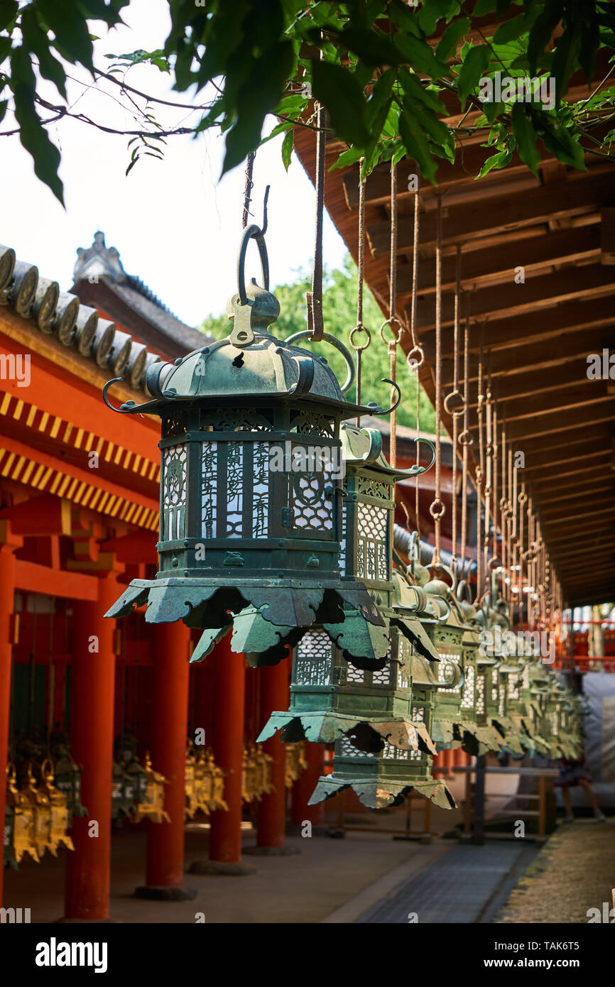 Traditional metal Japanese lanterns hang from a wooden roof at Kasuga ...