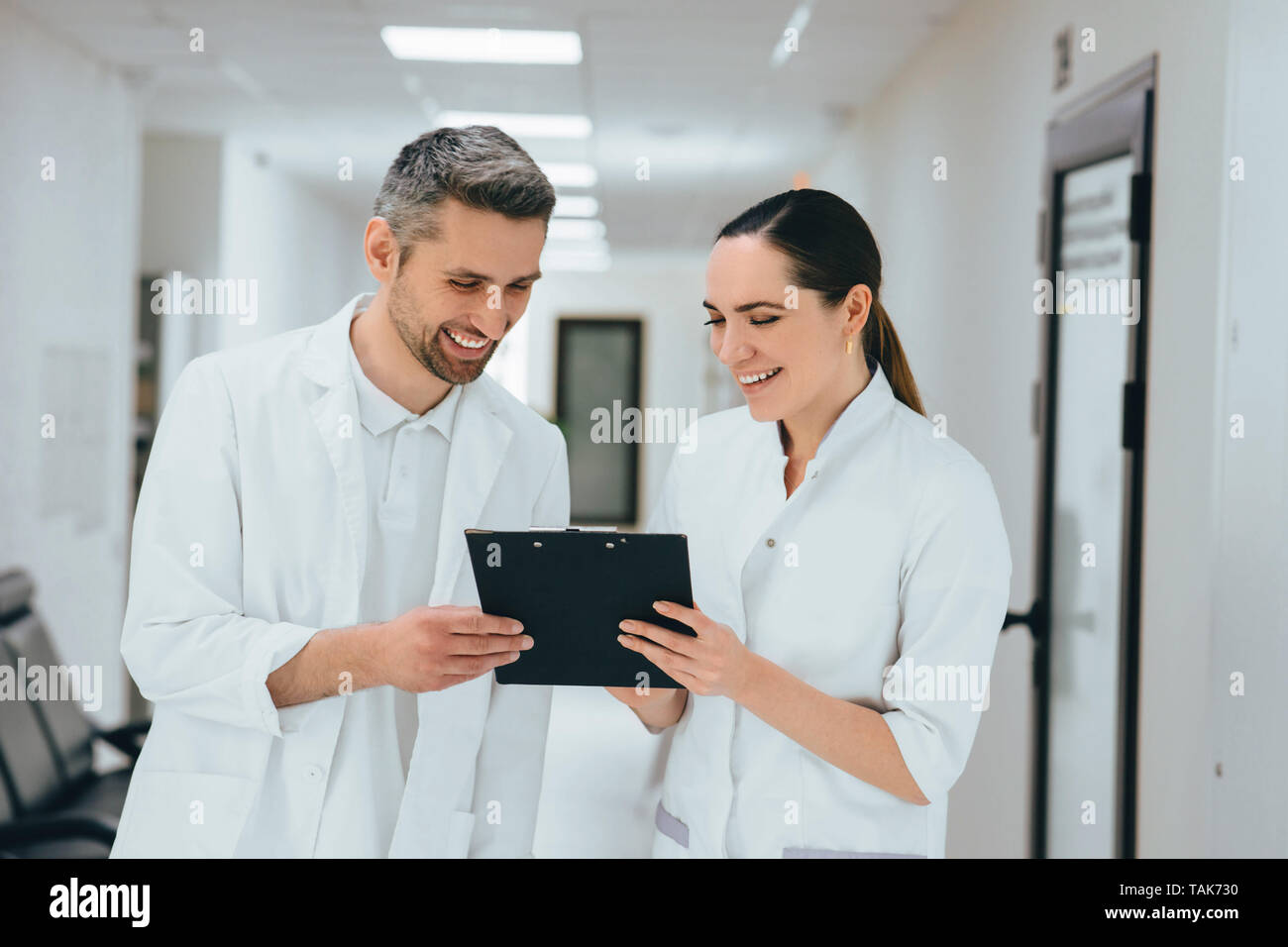 Two doctors conferring over a case standing at hospital corridor ...