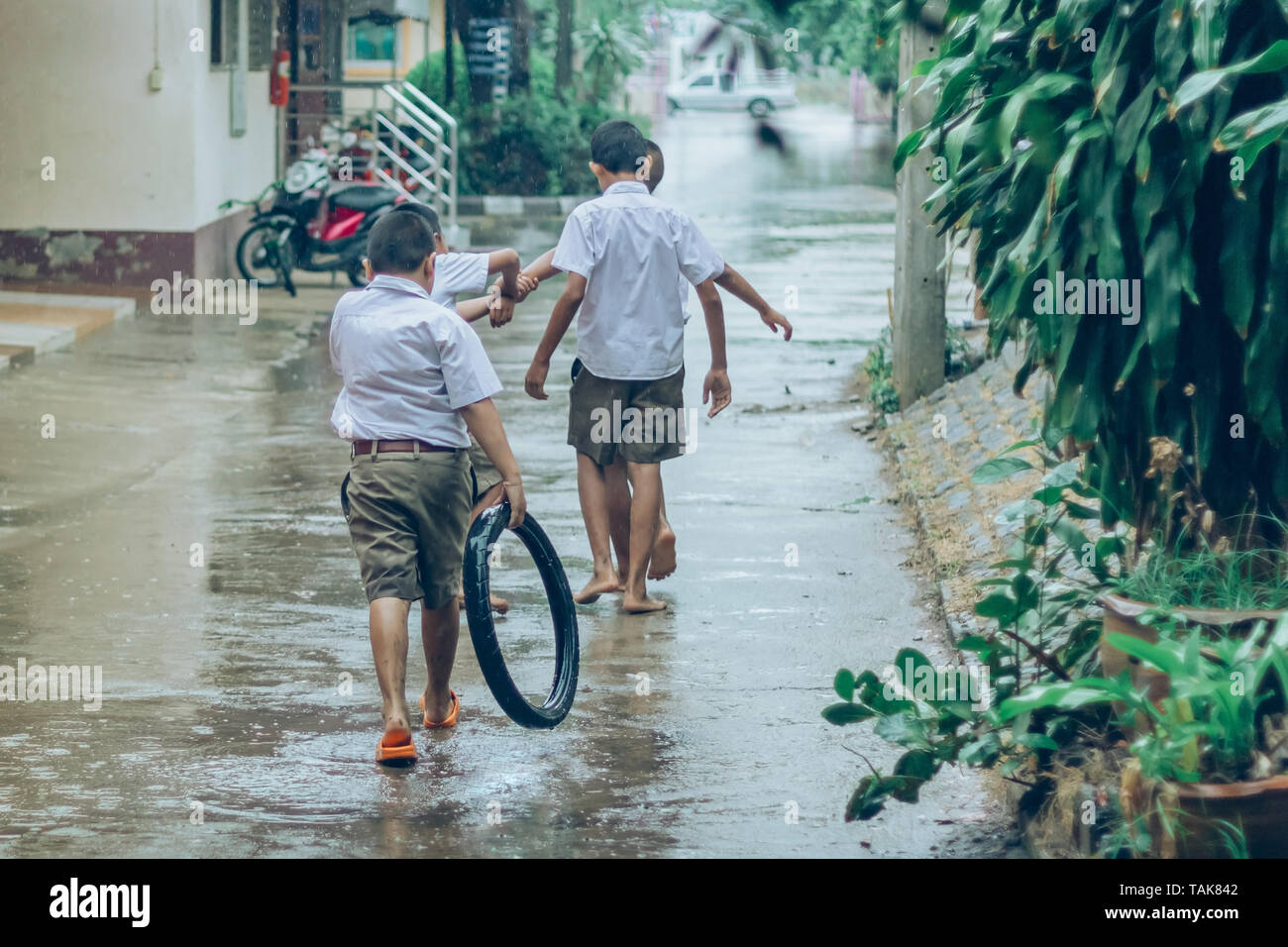 Boy students leave the classroom to walk on the street after heavy rain ...