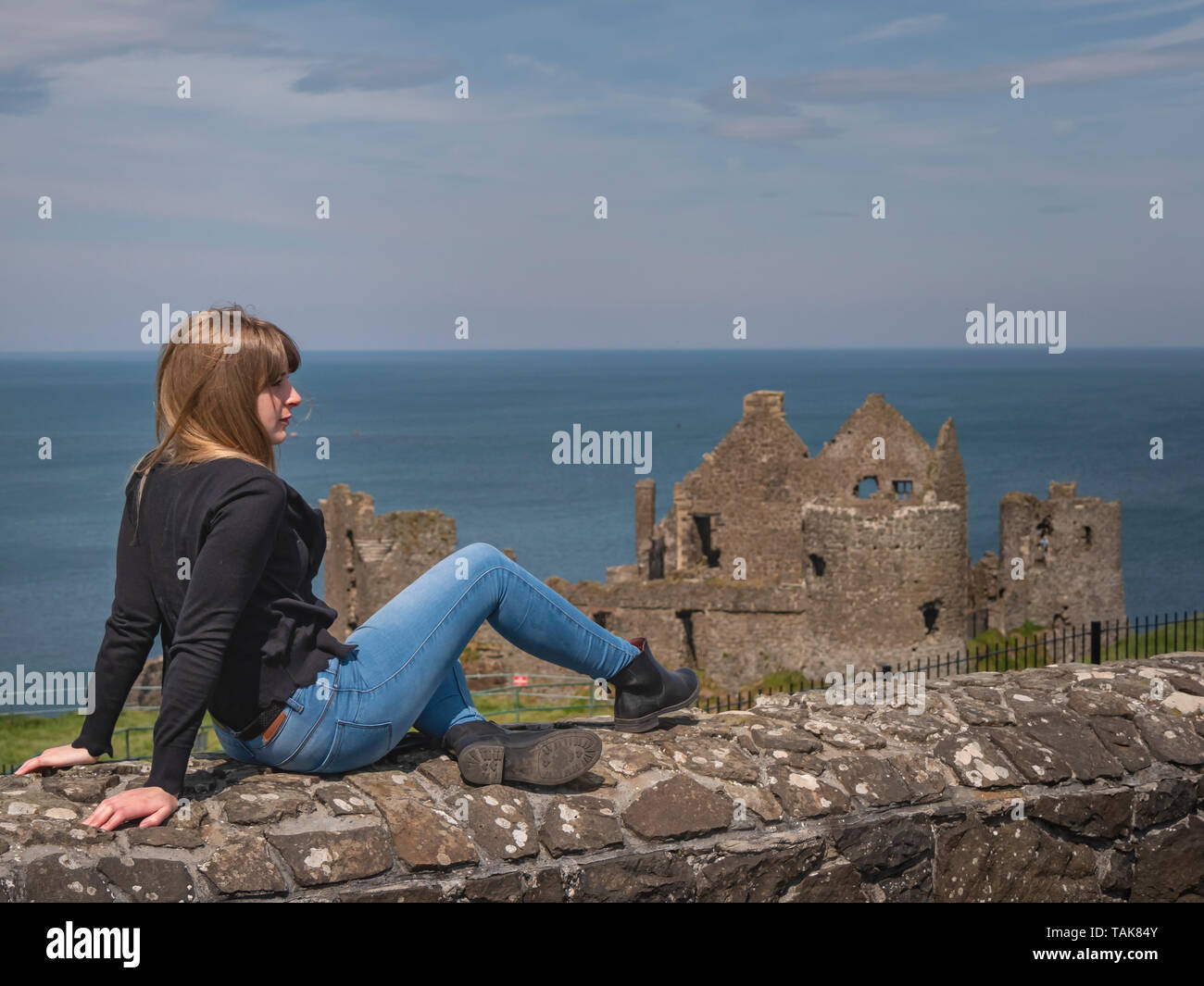 Girl relaxes on the wall at Dunluce Castle in North Ireland - travel ...
