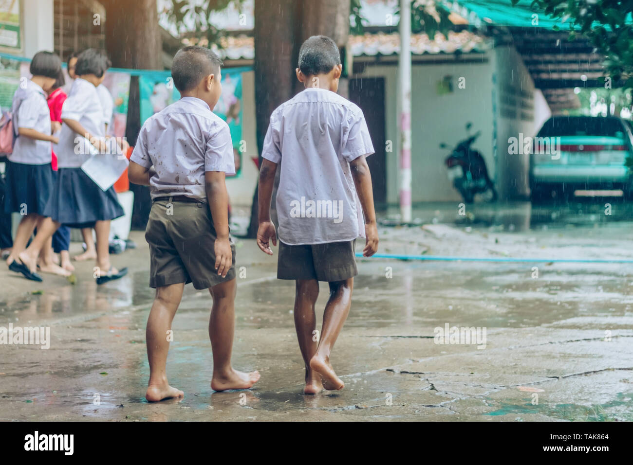 Boy students leave the classroom to walk on the street after heavy rain ...