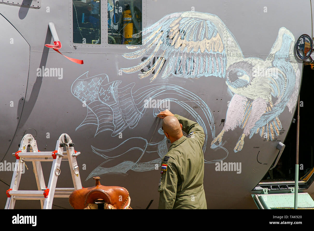 Air Force crewman chalking an eagle picture on the nose of a Lockheed C ...