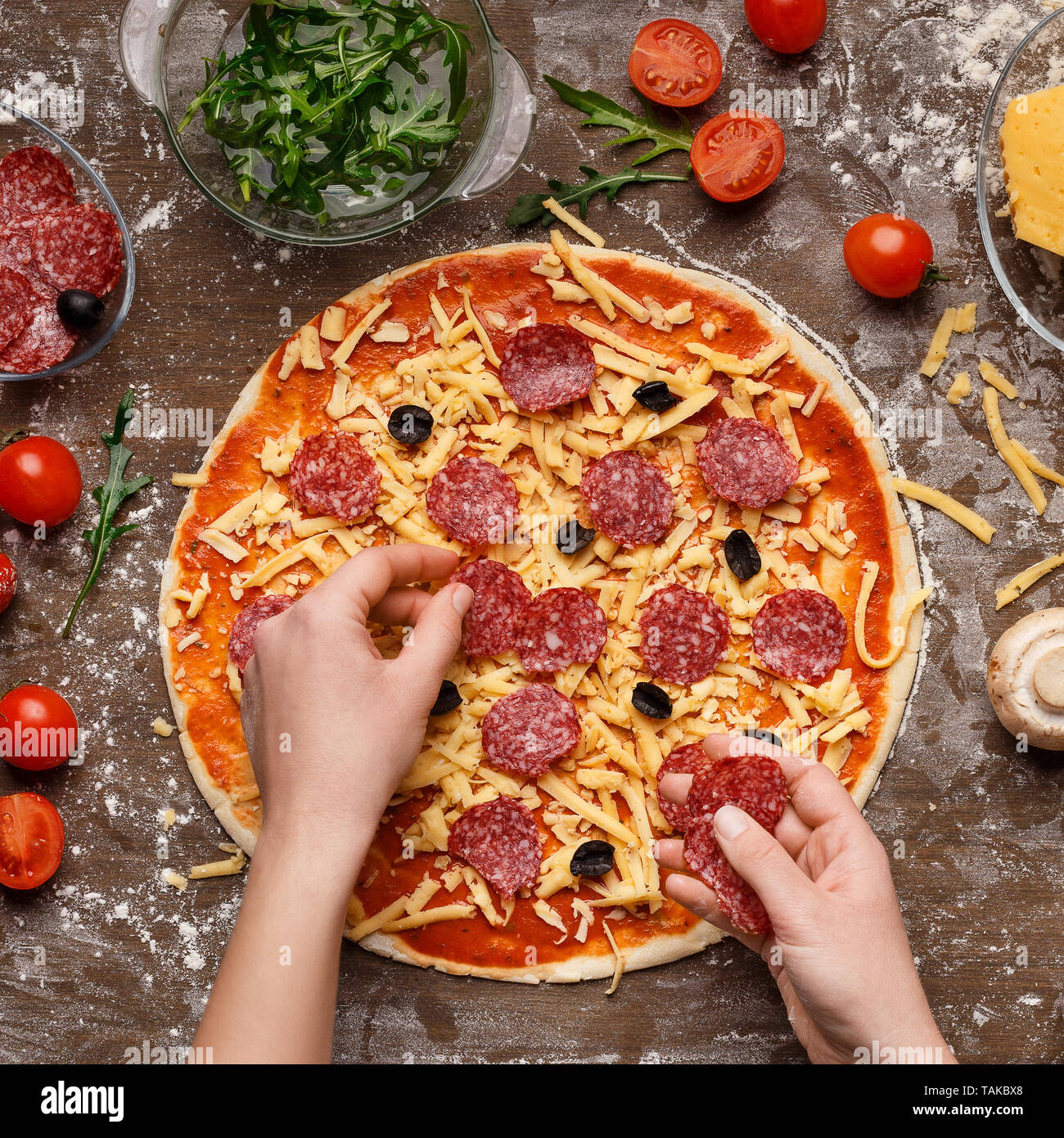 Chef Decorating Pizza With Black Olives And Salami Stock Photo - Alamy