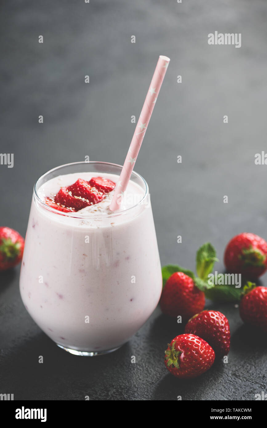 Strawberry smoothie milkshake in glass on black concrete background ...