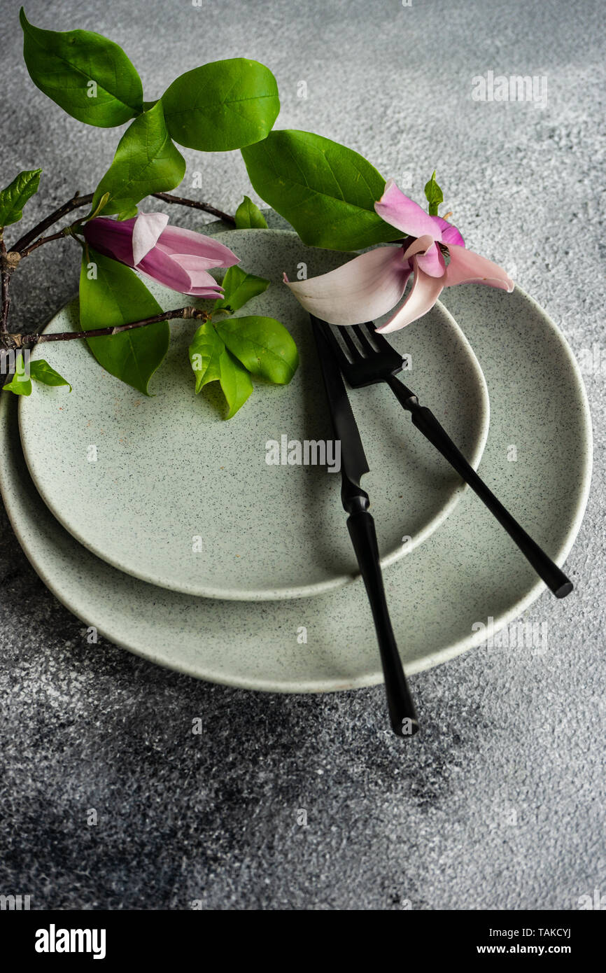 Spring table setting with magnolia blossom on grey concrete background ...