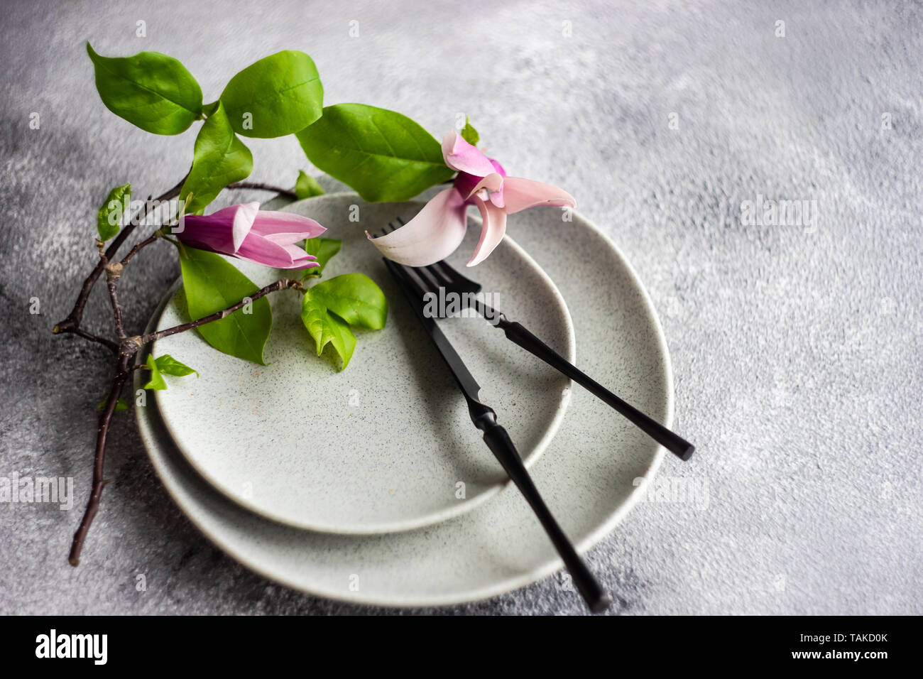 Spring table setting with magnolia blossom on grey concrete background ...