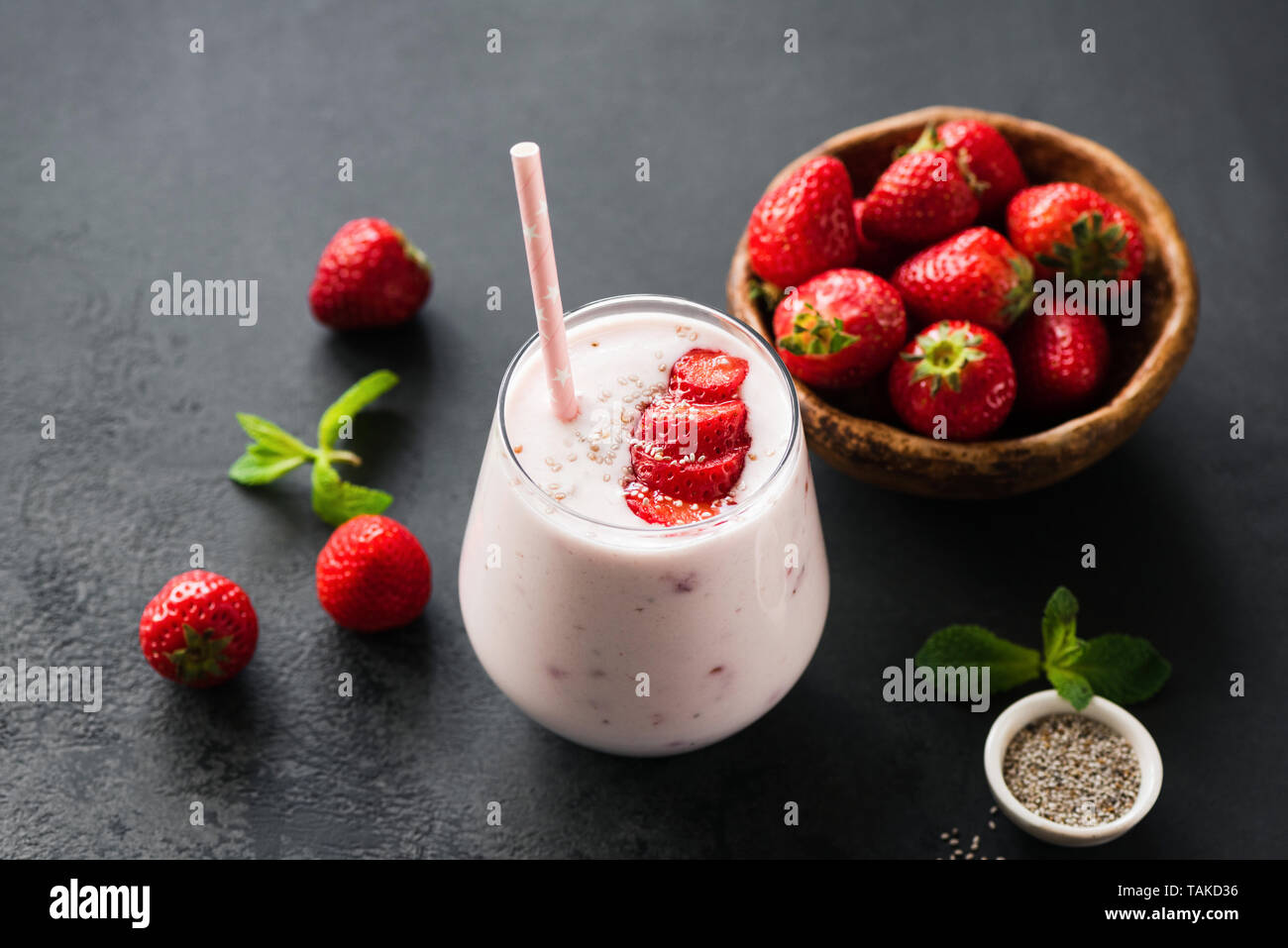Strawberry smoothie or milkshake in glass on black concrete backdrop ...