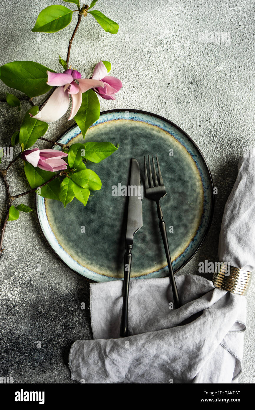 Spring table setting with magnolia blossom on grey concrete background ...