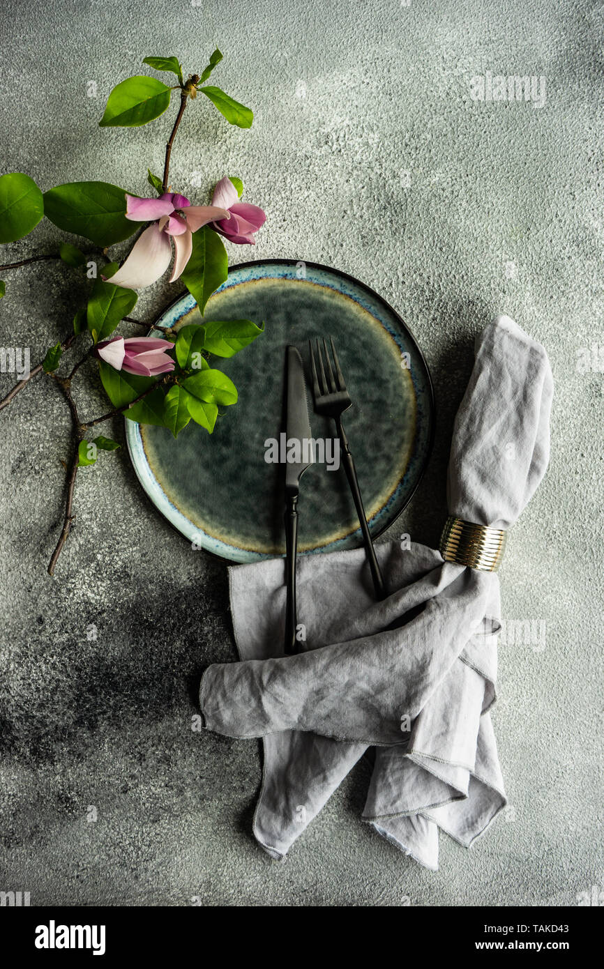 Spring table setting with magnolia blossom on grey concrete background ...
