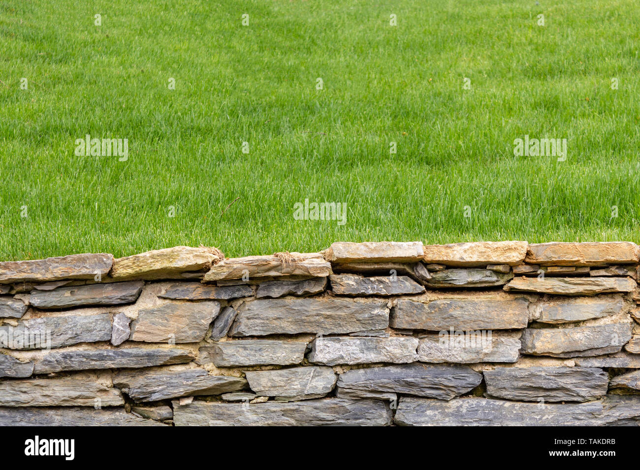 Natural stone wall and green grasses background Stock Photo - Alamy