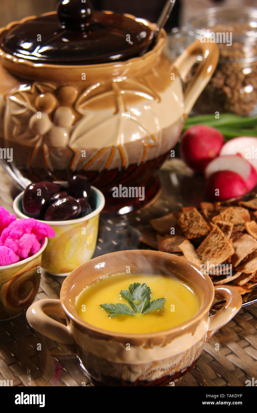 Hot and steamy Lentil soap in a bowl, and siders of: pickles, olives ...