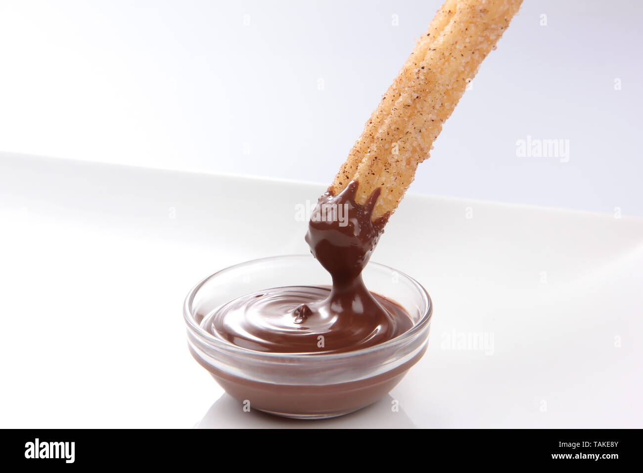 Single long piece of sugar cinnamon Spanish Churro dipping in a melted ...