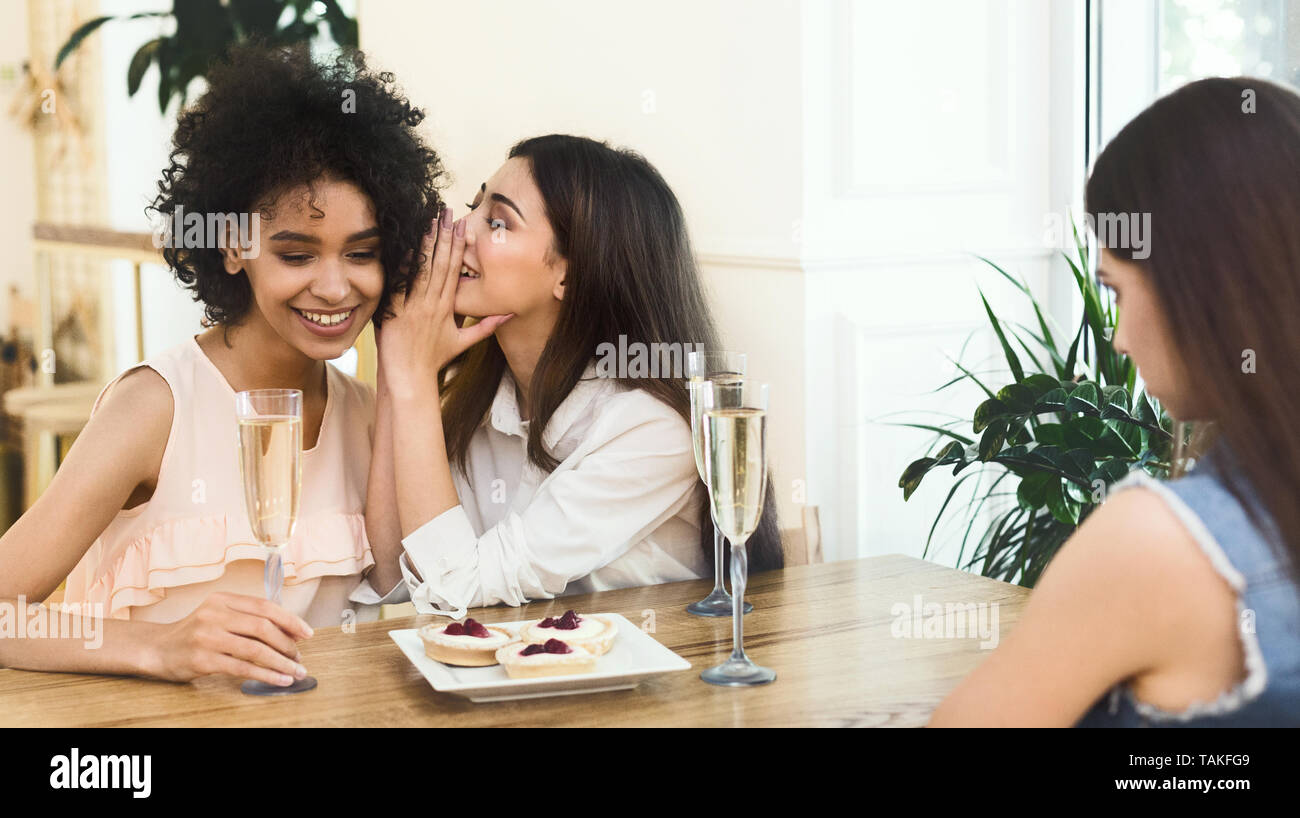 Two girls gossiping and whispering in front of third friend Stock Photo ...